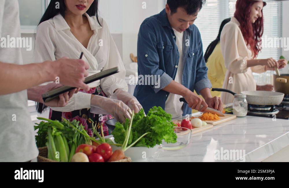 Man Helping His Female Friend with Recipe while Others Cooking Dinner ...