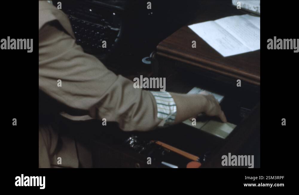 1940s: Secretary sits at typewriter and opens drawer, fetching a ...