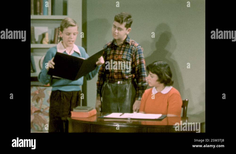 1940s: Kids in living room, boy reading from binder, girl writes at ...