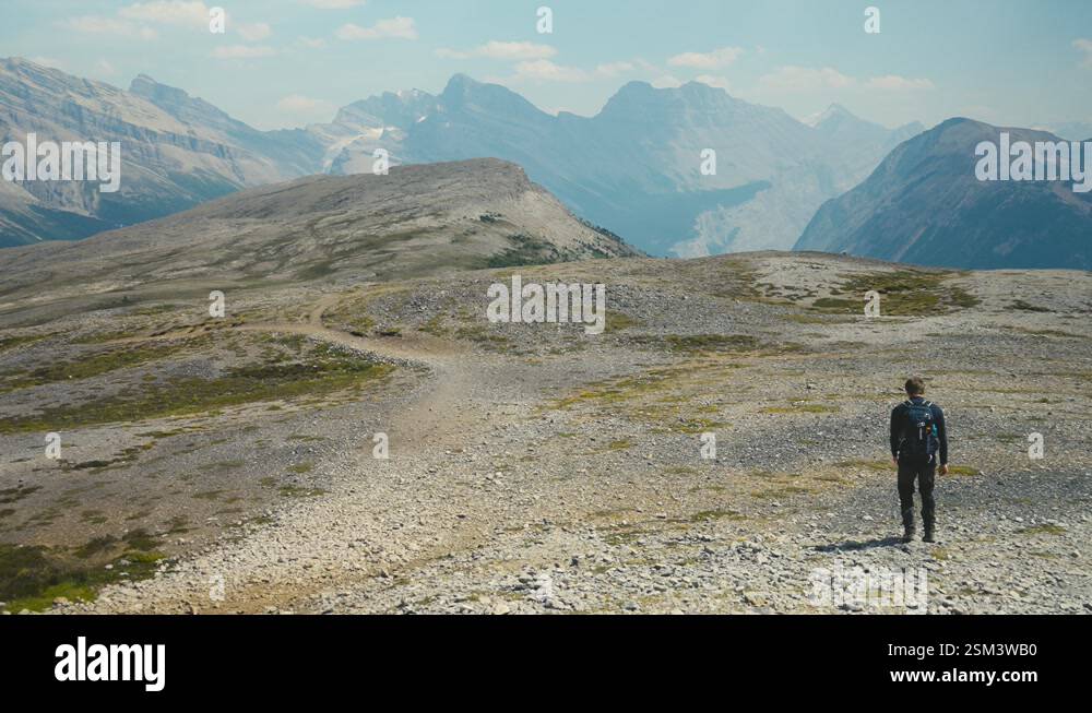 A man are hiking alone on a mountain peak in mountains of Alberta, on ...