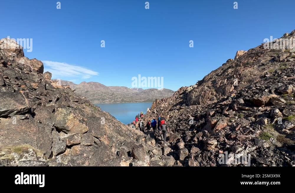 A group of hikers walking on the cliffs of Immikkeertikajik Island ...
