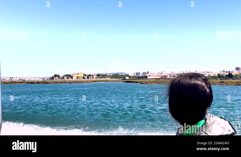 Woman rides a boat with hair blowing in the wind, gazing at the city ...