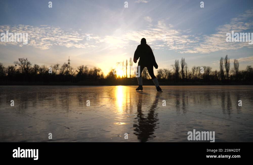 Girl skating on frozen river during beautiful sunset. Woman in figure ...