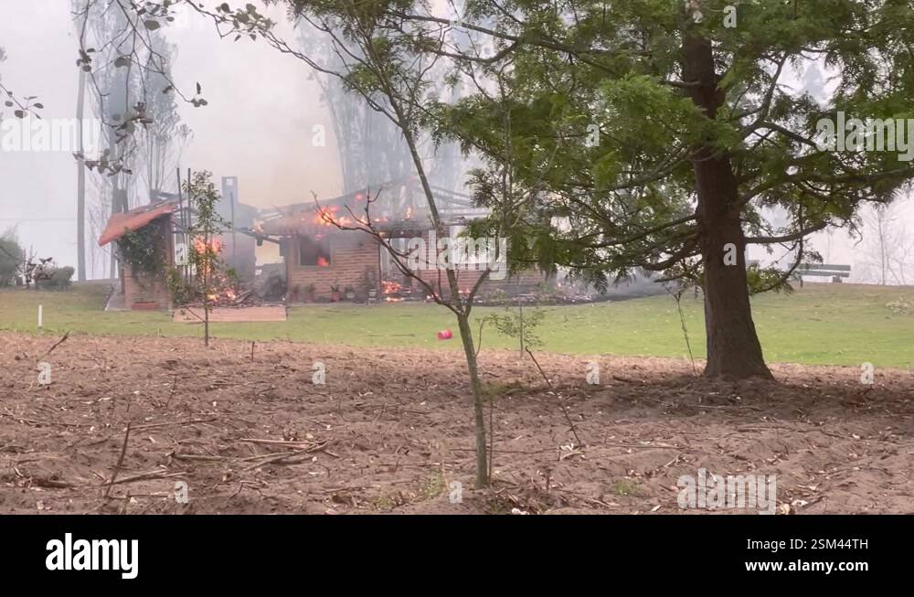 Flames rise from a burnt house destroyed by a wildfire. Fire has ...