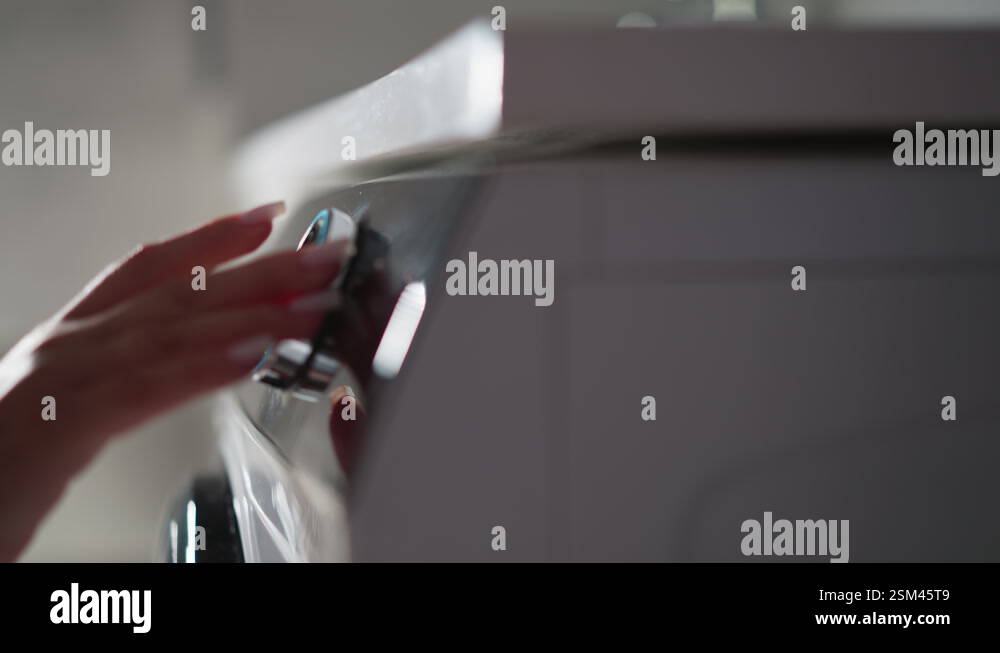 Female uses washing machine turning toggle switch in bathroom Stock ...