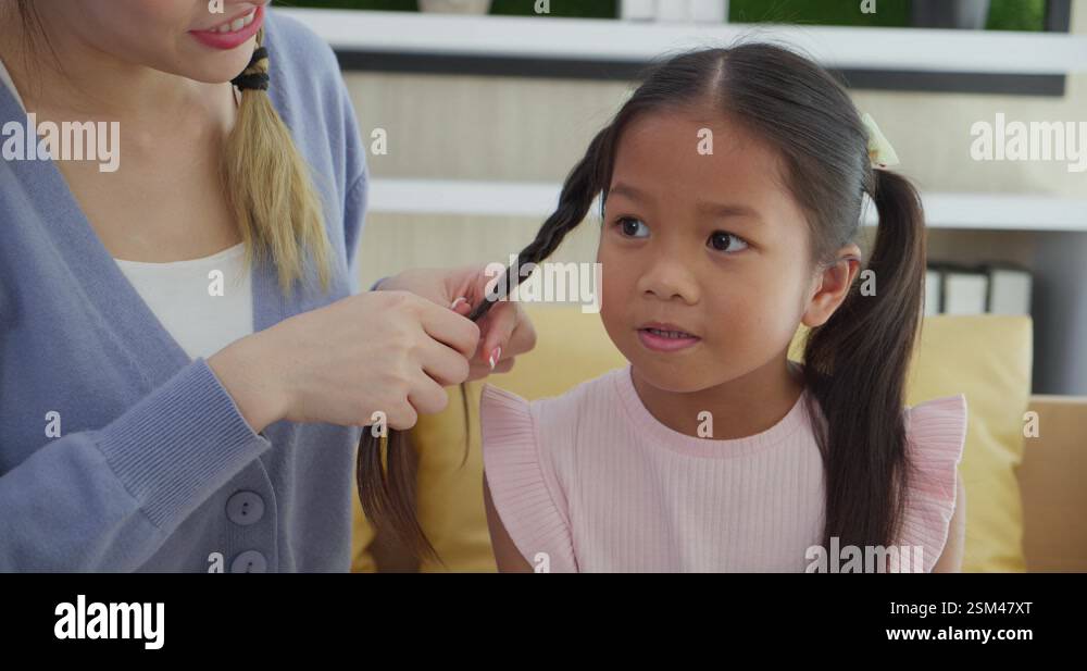Caring mother braiding pigtail to daughter. Mother braids pigtails for ...