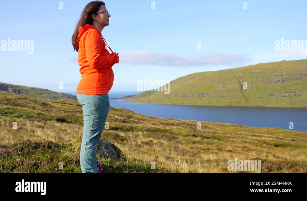 Relaxed woman on a mound admiring the Faroese beauty of Lake ...