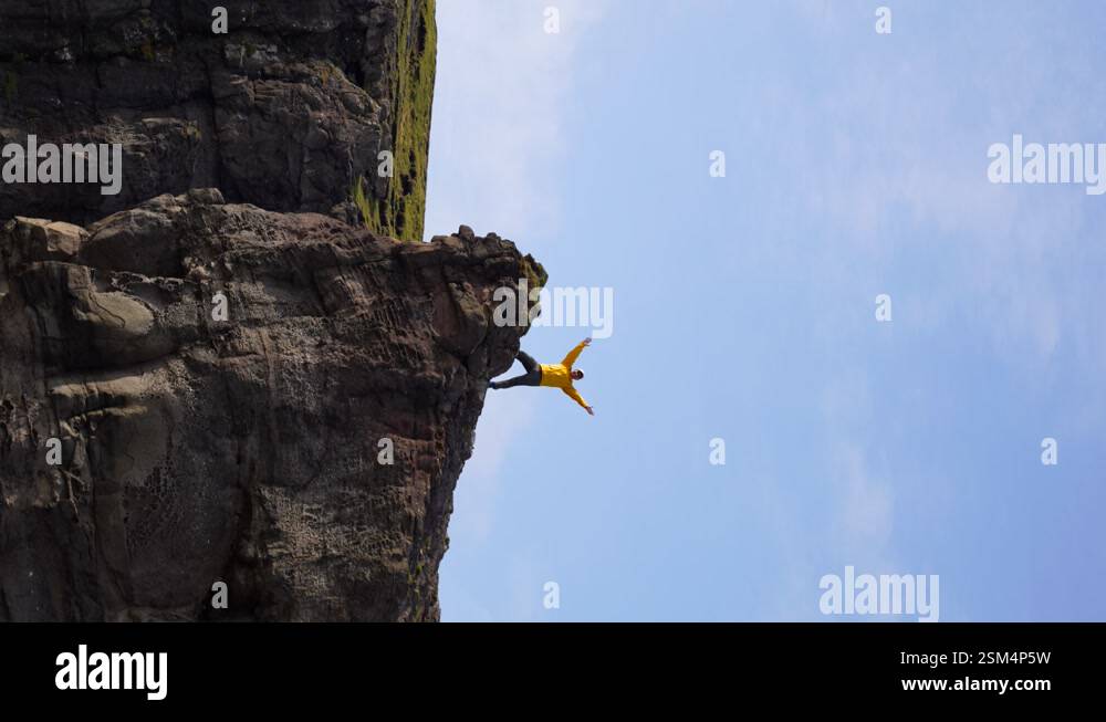 Man with yellow raincoat opening his arms at Traelanipa cliff edge Stock Video Footage - Alamy