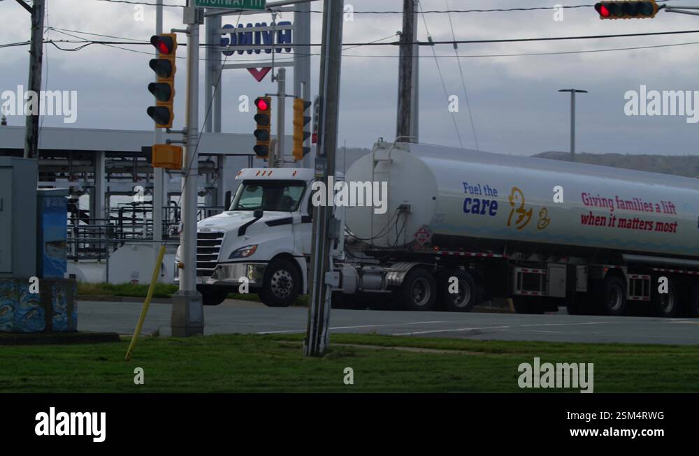 Big fuel tanker truck drive down the road and stops at a traffic light ...
