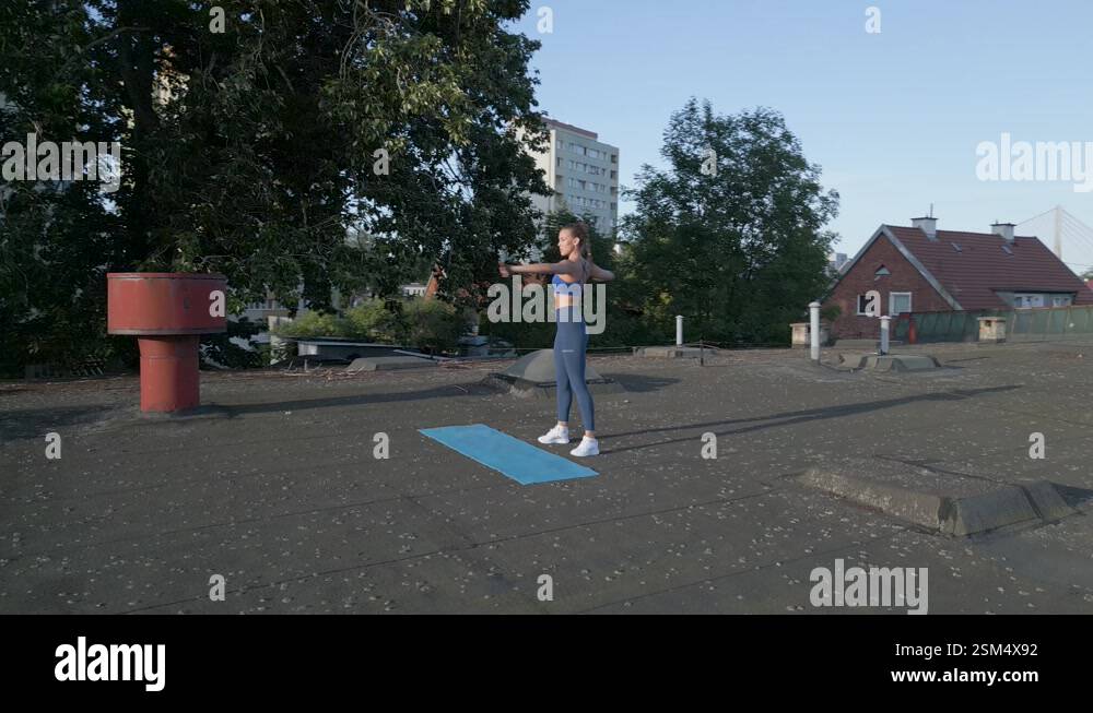 Wide tracking shot around a woman as she does stretches on a rooftop ...