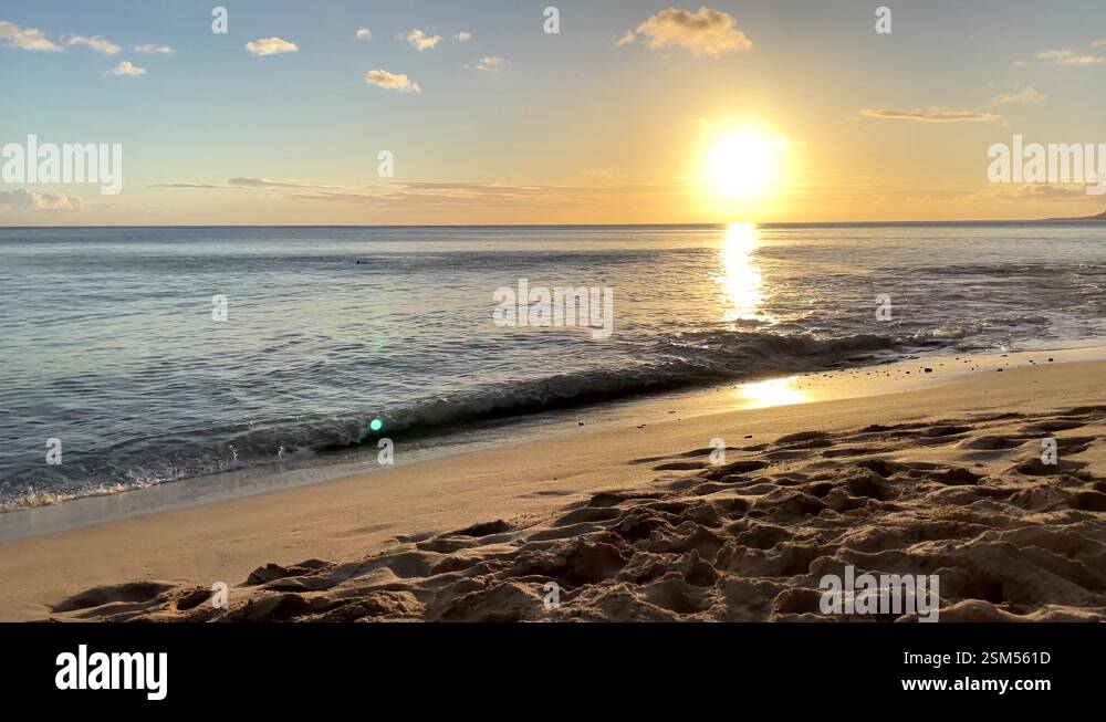 Bright golden sun casts ray of light across open ocean as gentle waves ...