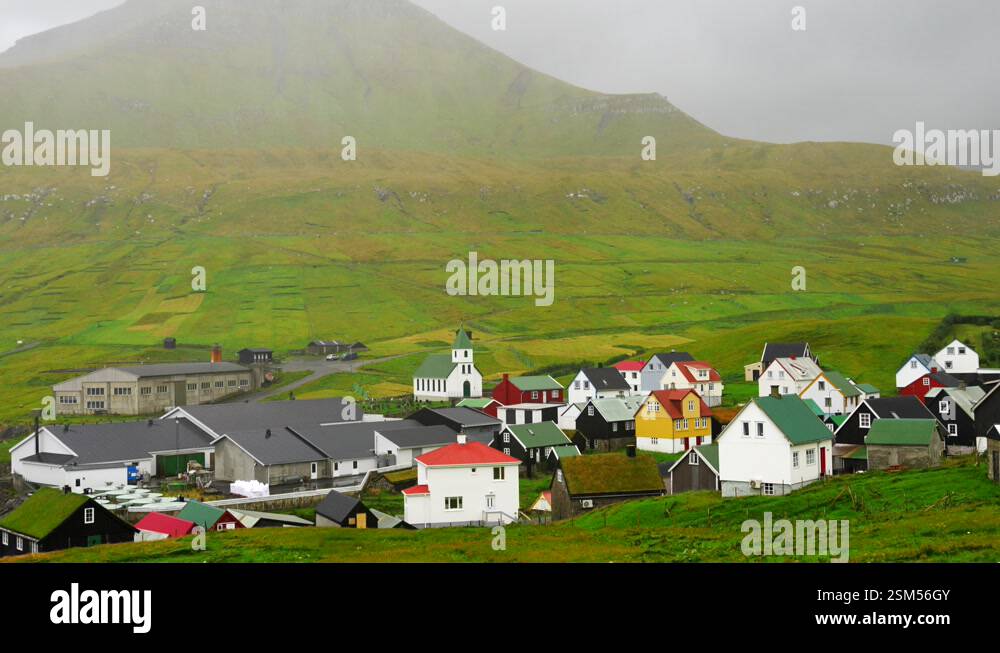 Pan across peaceful valley filled with fog over turf roof homes in ...