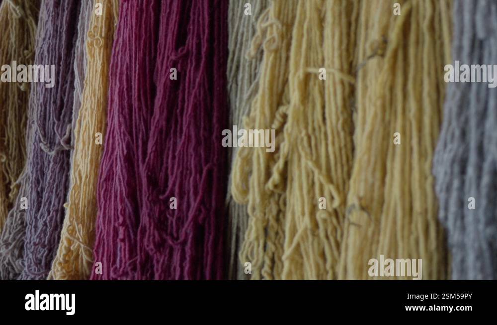 Slow panning shot showing multiple batches of colourful yarn hanging on ...