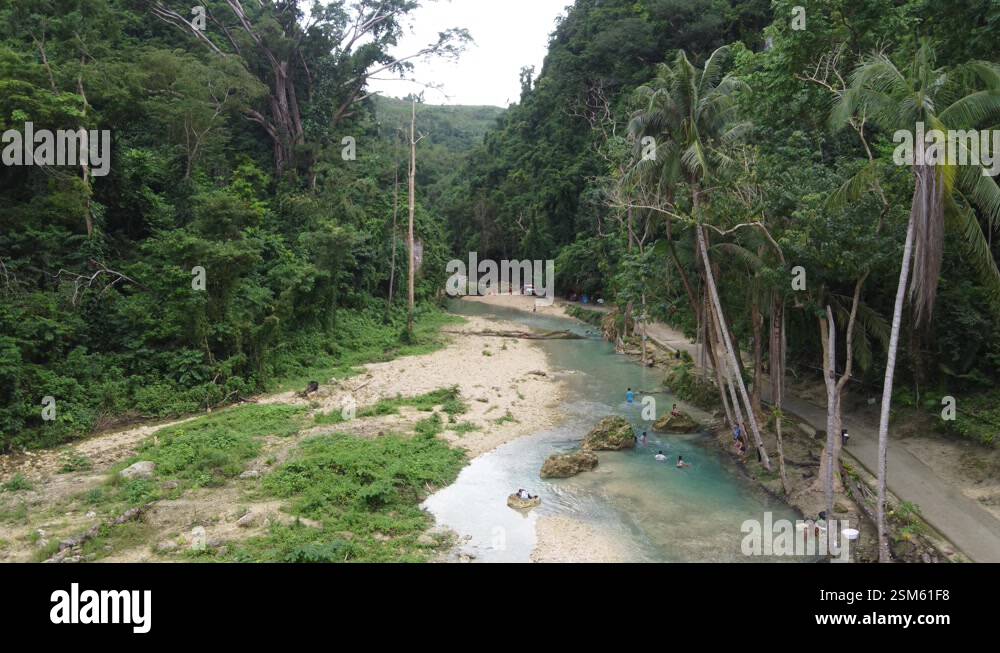 Filipino women doing laundry and swimming in Creek blue water amid lush ...