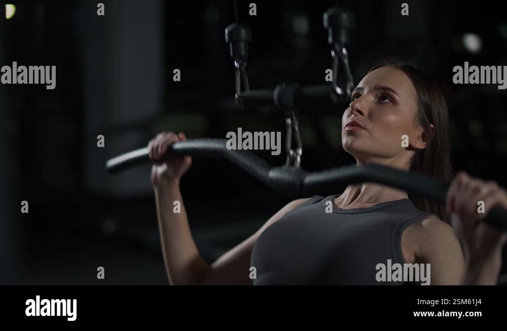 Sporty woman in the gym lifting blocks on gym machine, strength ...