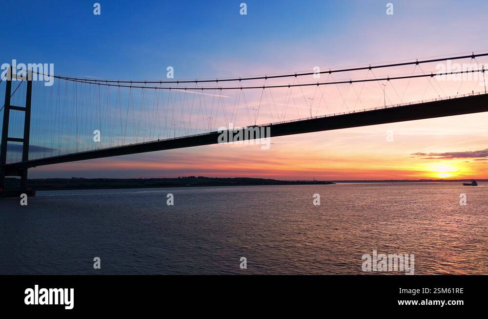 Humber Bridge bathed in the warmth of sunset, with cars seamlessly ...