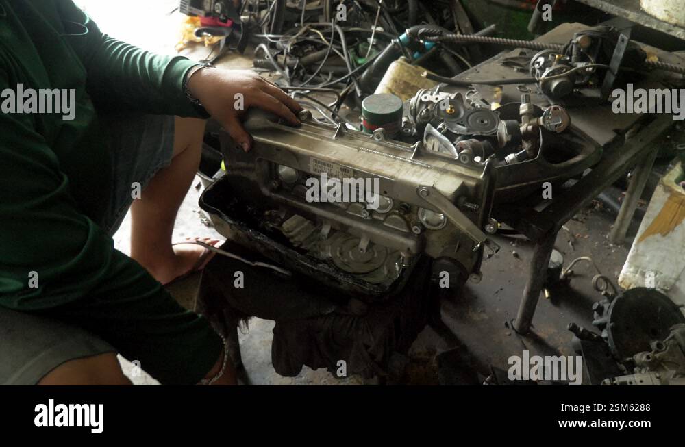 Hands of a man seen pouring gasoline on an engine block disassembled ...