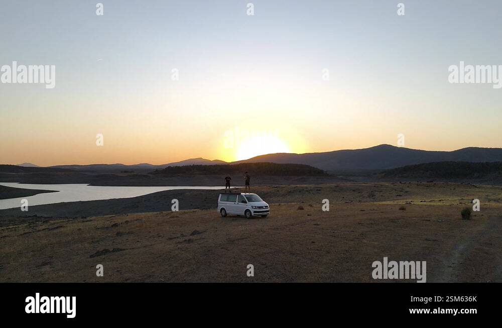 wo young people on top of a van while the drone zooms out and shows the ...