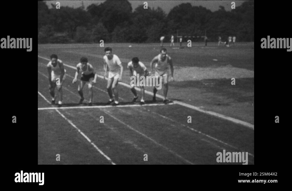 1940s: Man runs on track around field. Several runners on starting line ...