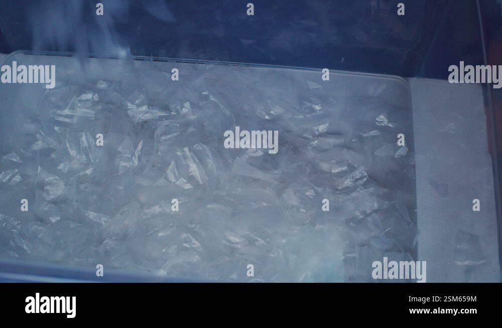 Plastic recycling.Shredded pieces of plastic film fall into a plastic ...