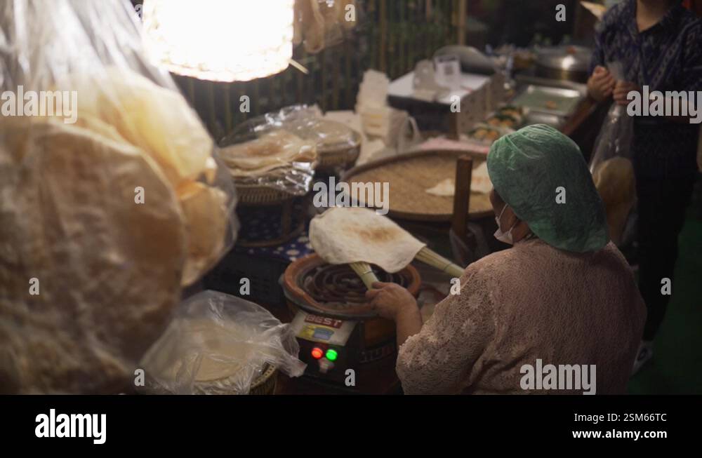 Two Thai women are baking bread at a street food market in Bangkok ...