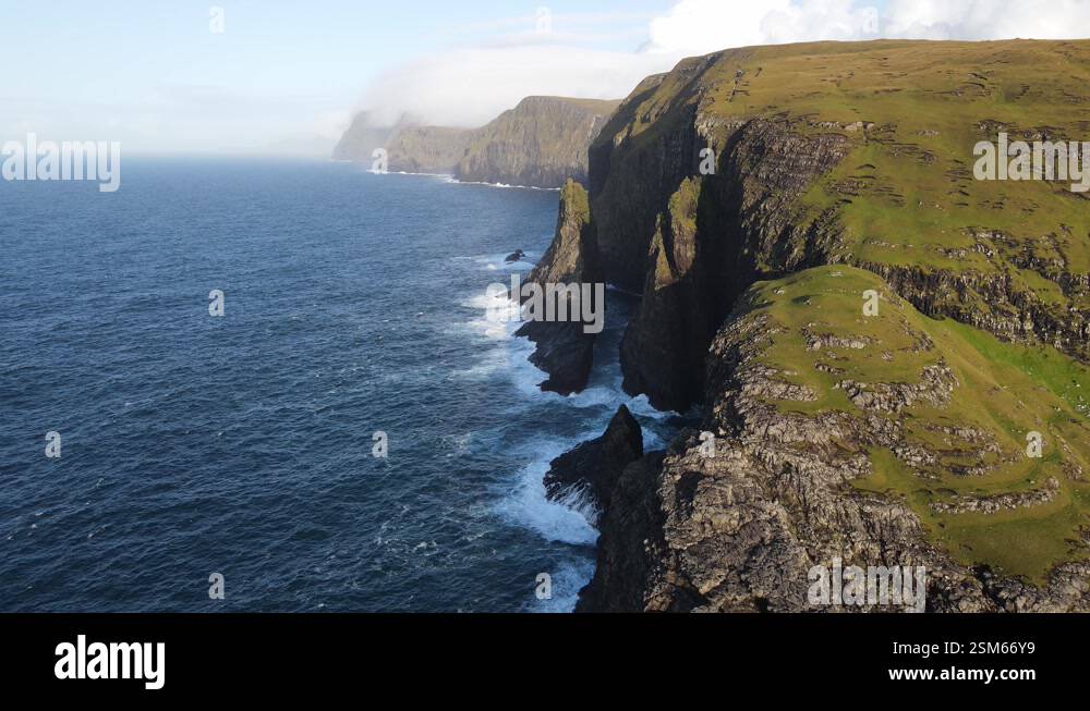 Distant drone footage of steep cliffs with a rising sun near the Stock ...