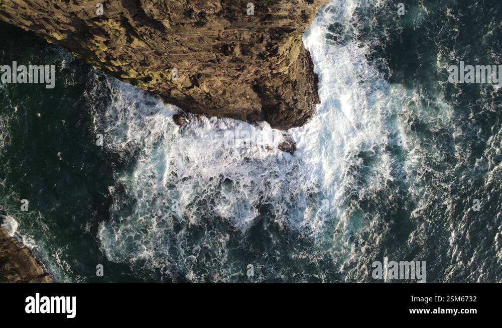 Rising top-down drone footage of a very steep cliff on the Vagar island ...