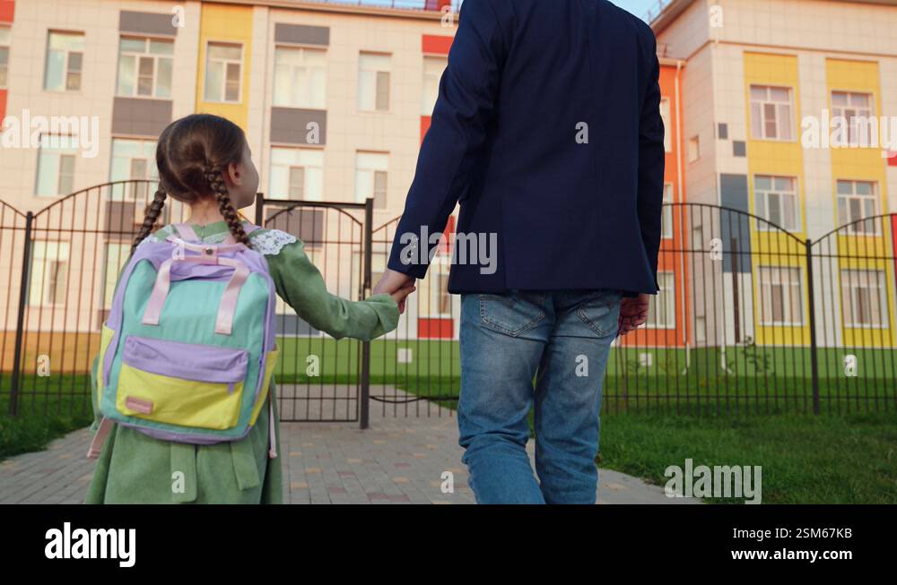 The father holds the hand of a first-grader with a backpack. Happy ...