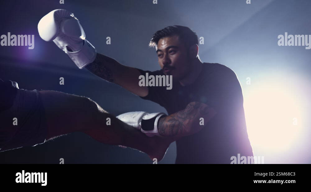 Fighter dodging leg kick inside ring match. Man wearing boxing gloves ...