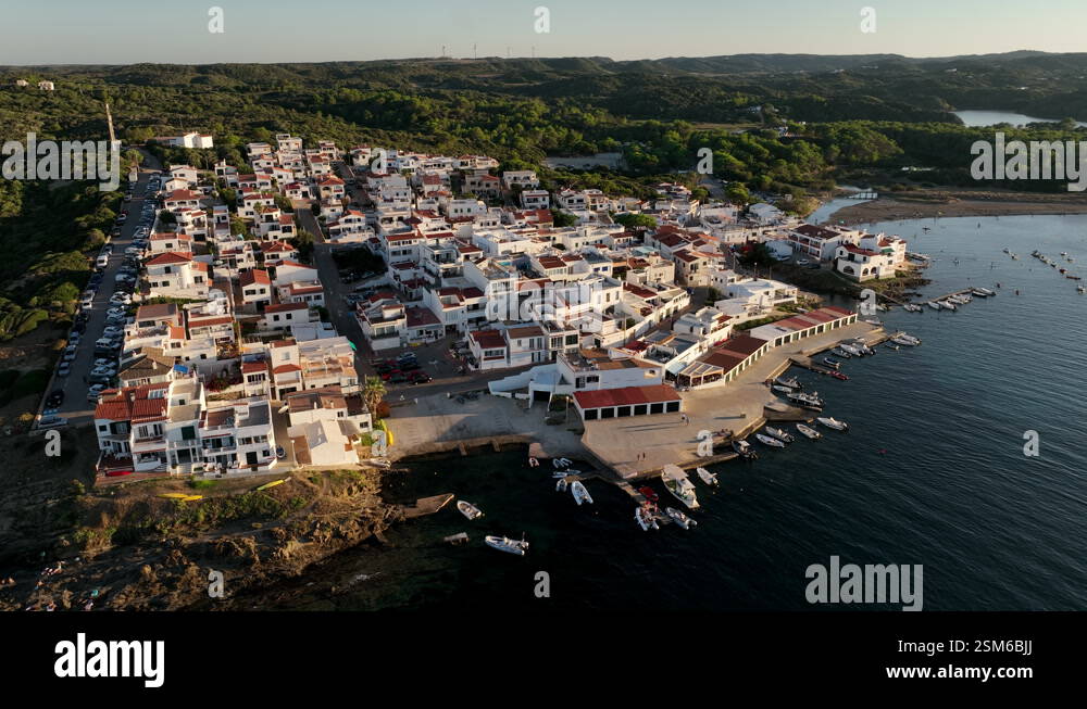 Bird's-eye panorama of Es Grau, Minorca, nestled between verdant hills ...