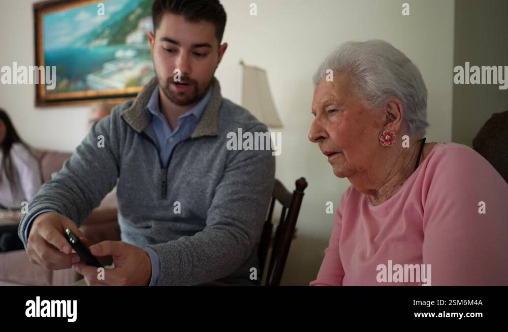 Grandson teaching elderly senior old woman grandmother how to use a ...