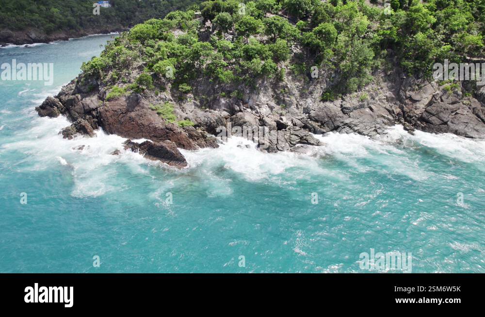 Tranquil aerial wide shot of water crashing on the rocks shore sand ...