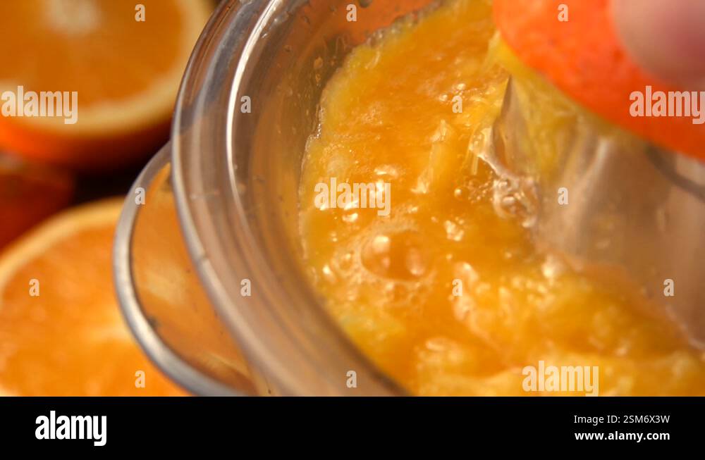 Super close-up of the orange juice squizzed from the half of an orange ...