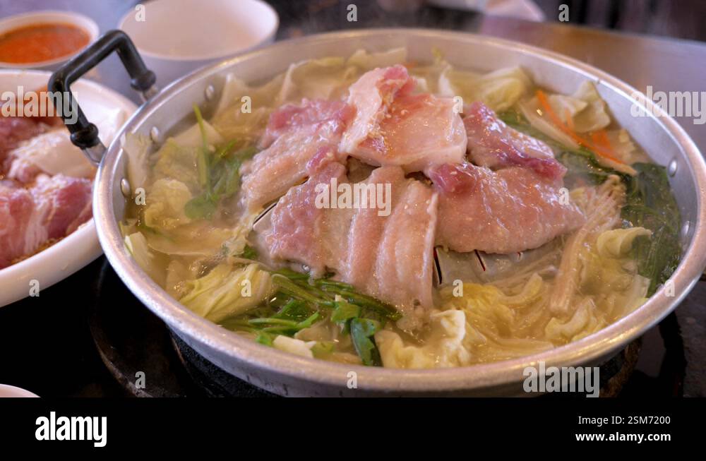 Steaming hot pot filled with thinly sliced meat and loads of vegetables ...
