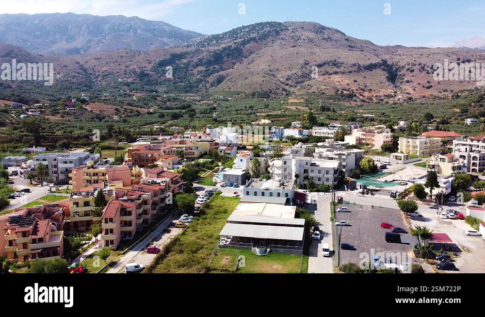 Cinematic aerial view of township and mountain range in background in ...