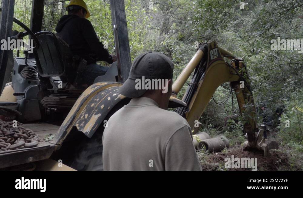 A backhoe loader digging in the forest for the installation of concrete ...