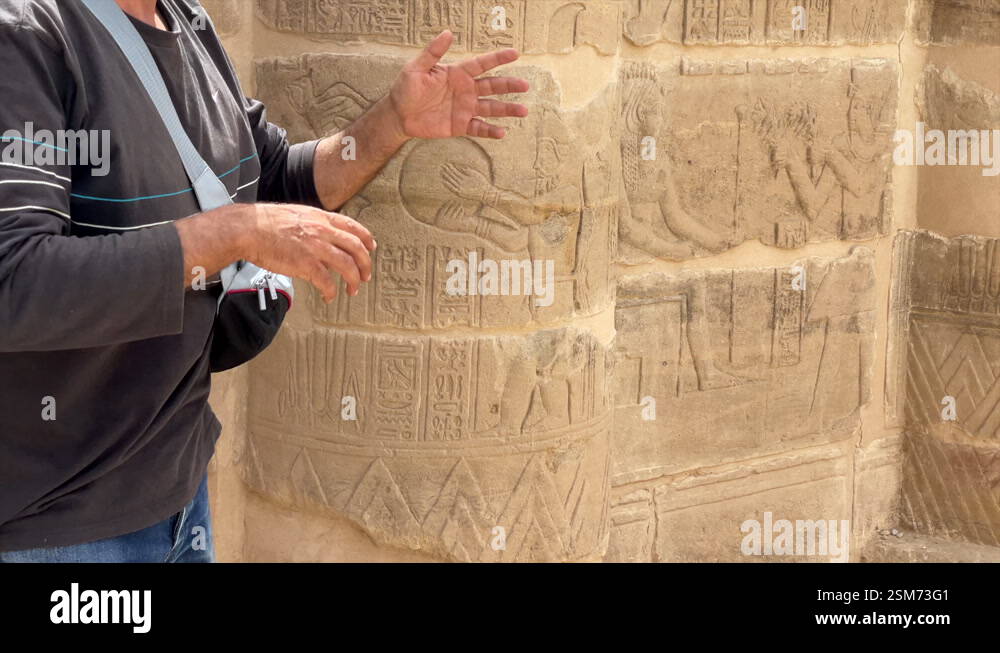 Man pointing at egyptian hieroglyphs in isis Temple. Hieroglyph of ...