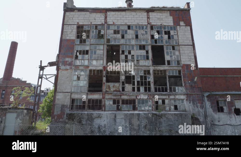 large, abandoned building with broken windows. The building is in a ...