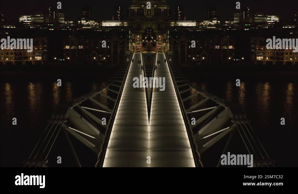 People walking on footbridge over river in night city center. London ...