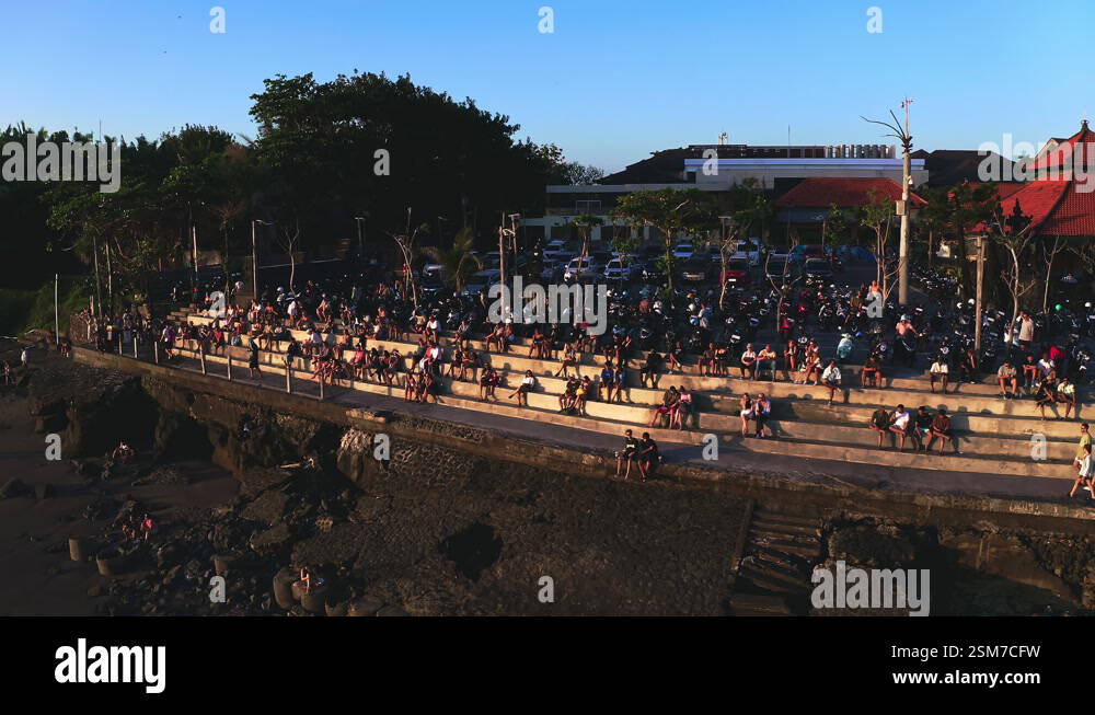 Crowd of people sitting on Canggu beach stairs lit by sunset, Bali ...