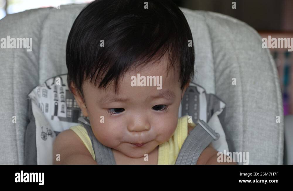 Happy 1years old Chinese baby boy having food while sit on baby chair ...
