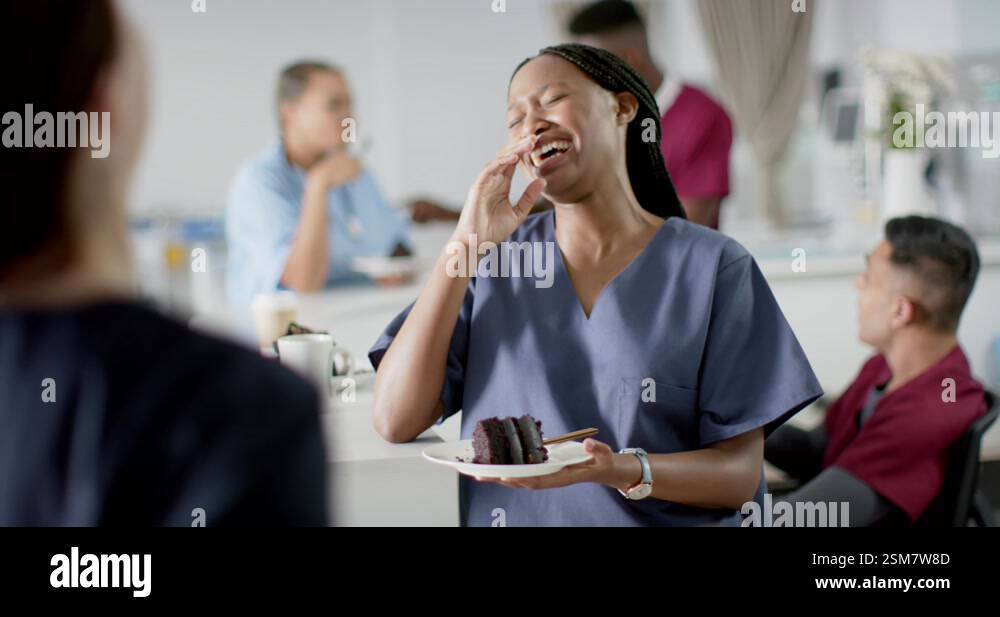 Diverse male and female doctors eating birthday cake at reception desk ...