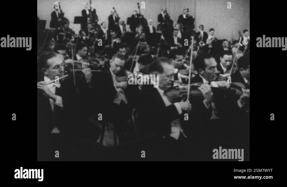 1950s: Men playing the flute, violins start to play. Conductor at the ...