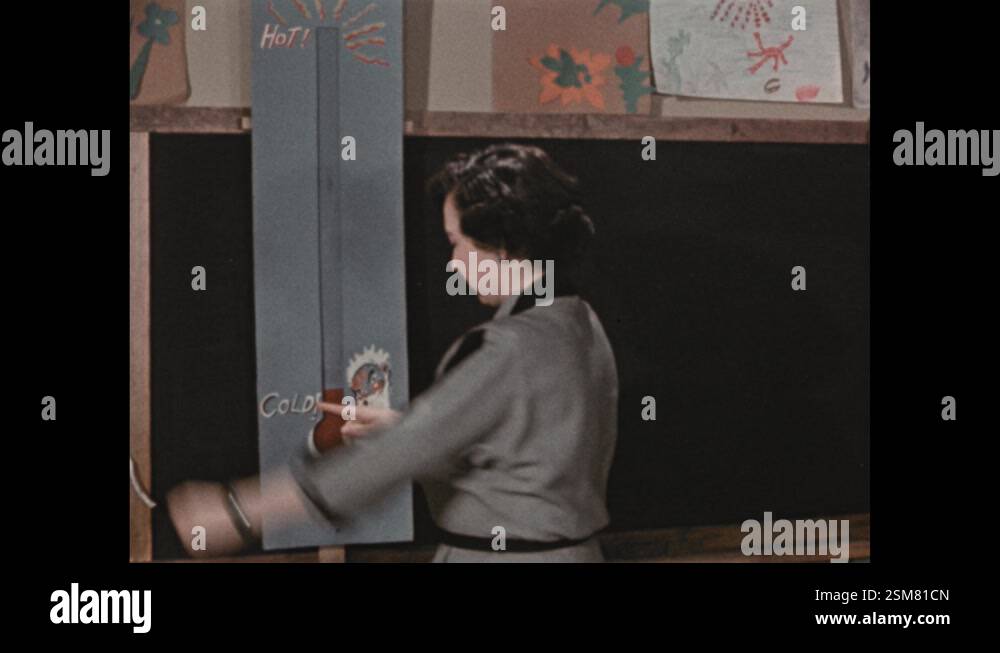 1960s: Classroom. Teacher adjusts fake thermometer display. Woman ...