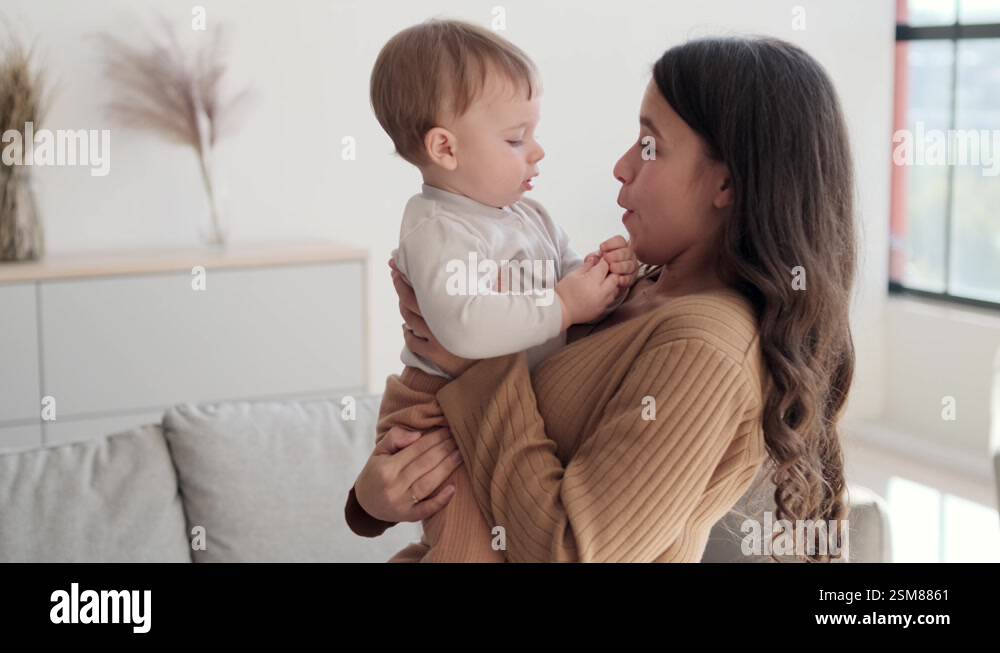Mother Holding Little Son and Showering Him with Kisses in the Living ...
