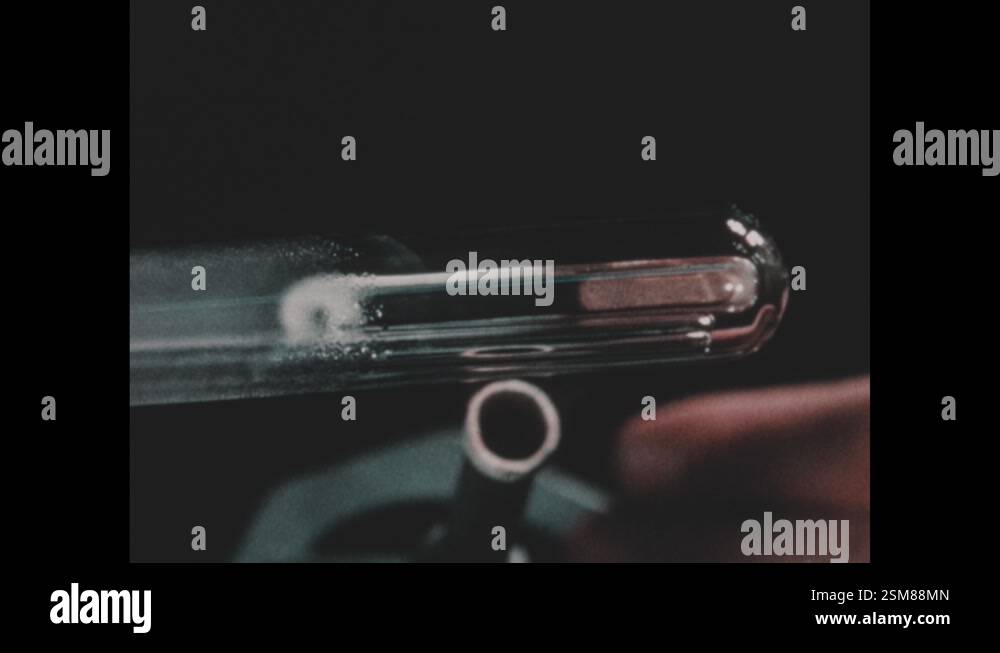 1950s: Hands point to glowing copper oxide in test tube above Bunsen ...