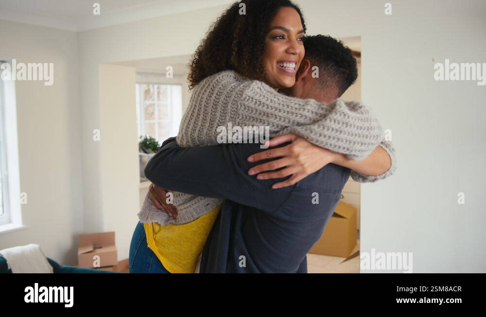 Excited Couple Hugging As They Unpack Boxes In New Home On Moving Day ...