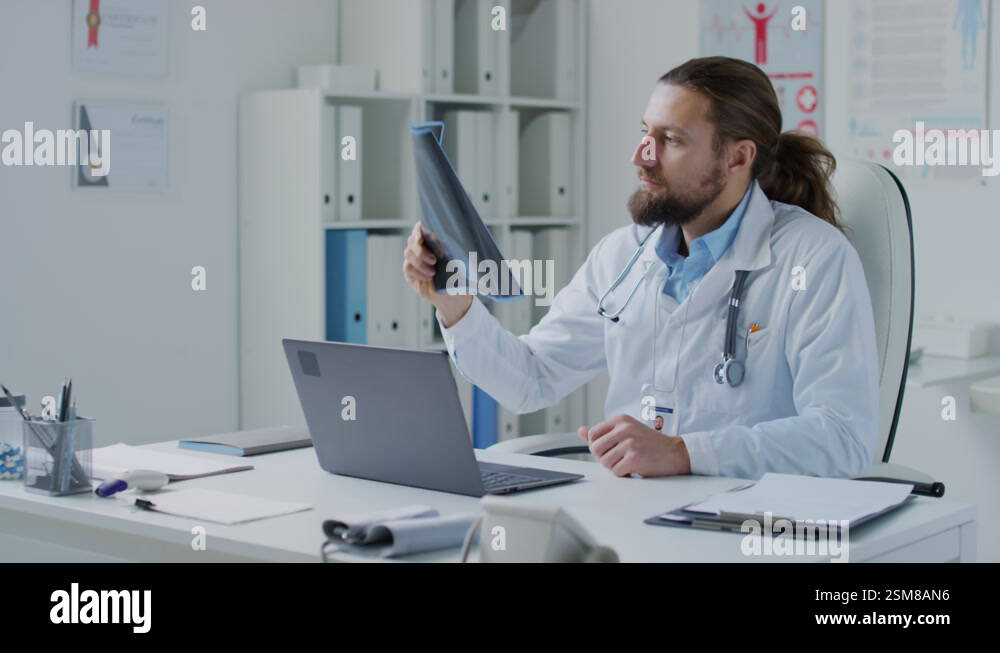 Male Doctor Looking at Chest X-ray and Entering Data into Laptop Stock ...