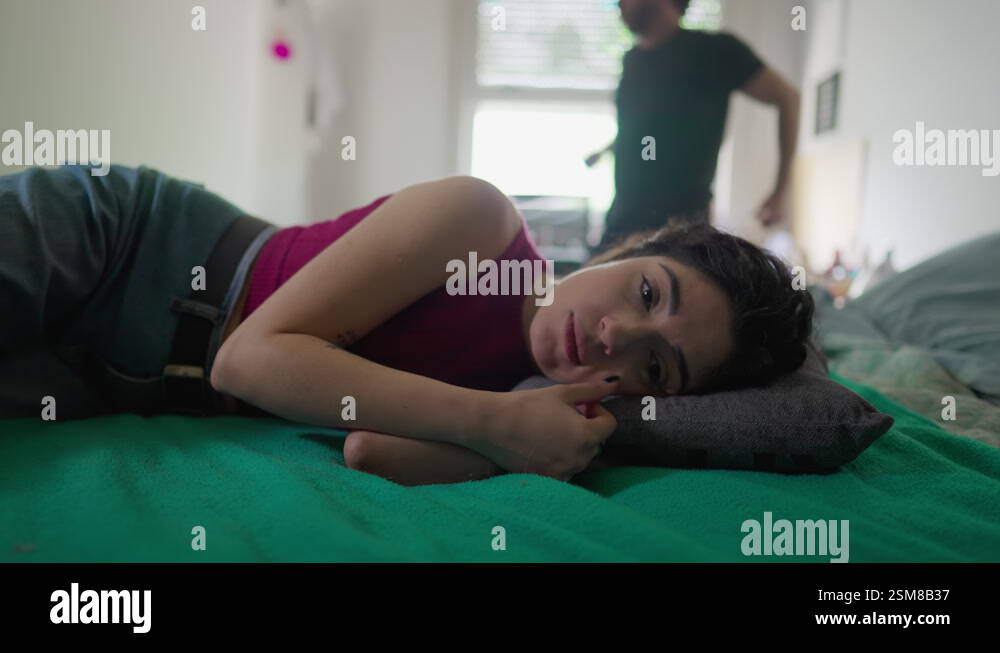 Couple in crisis: Depressed young woman lying in bed with sad ...