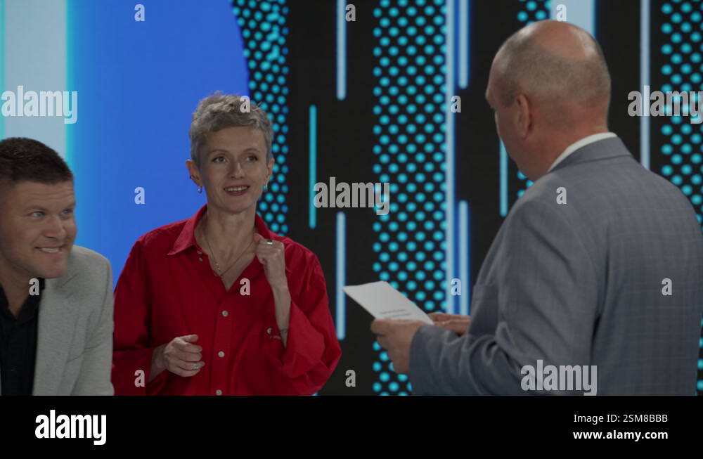 Host talking to contestants during recording of a fictional morning ...